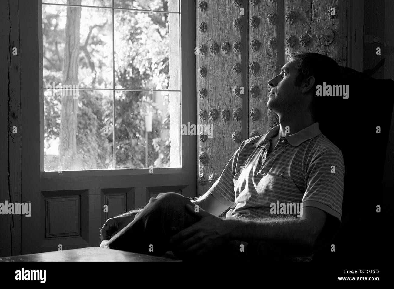 Mature man sitting, looking through the window. Black and white Stock ...