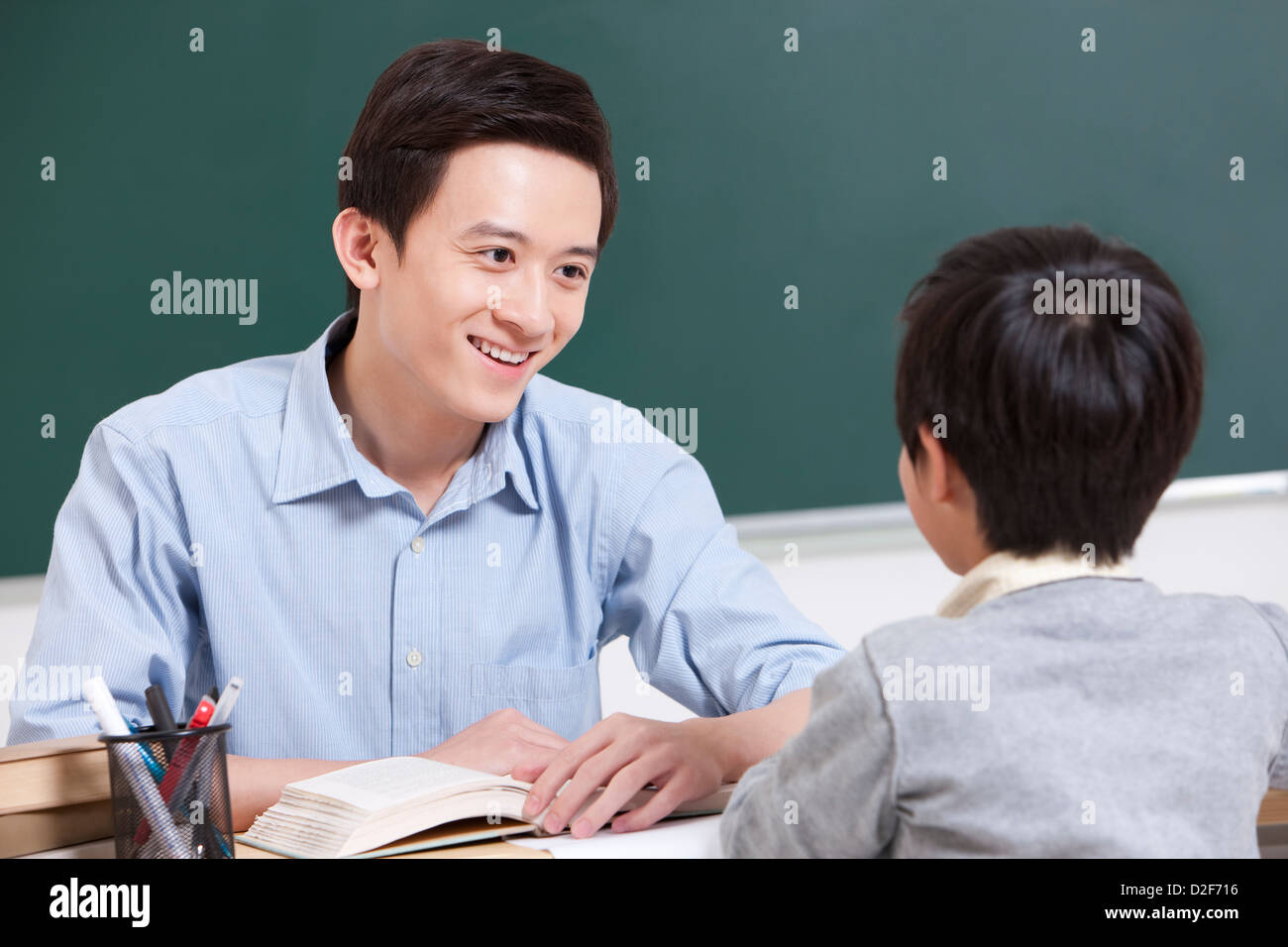 Smiling teacher and schoolboy having a conversation in classroom Stock ...
