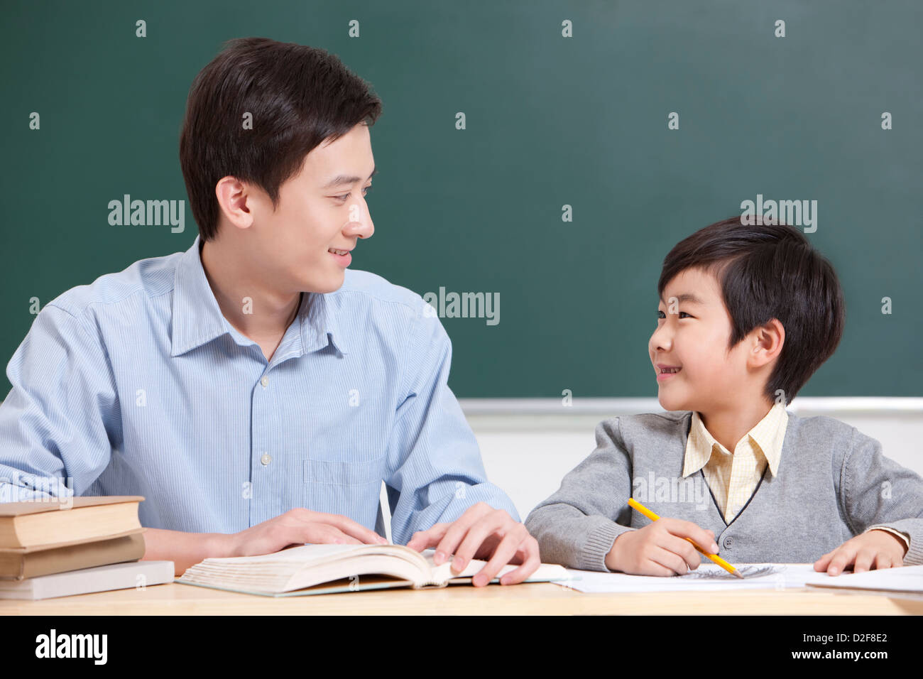 Happy schoolboy and teacher face to face in classroom Stock Photo - Alamy