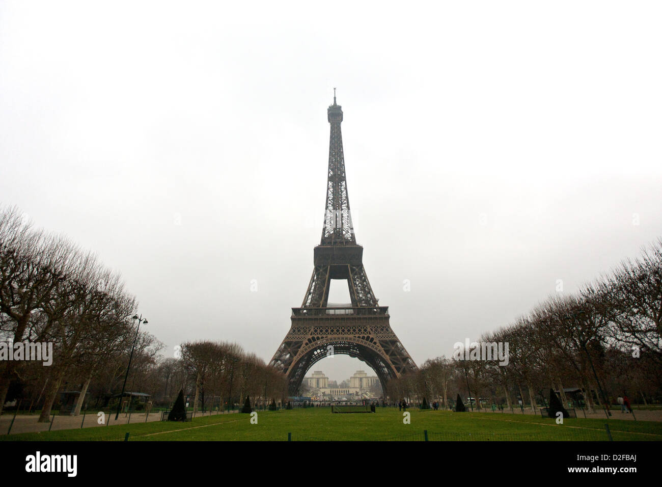 A classic view of the Eiffel Tower framed by symmetrical rows of trees ...