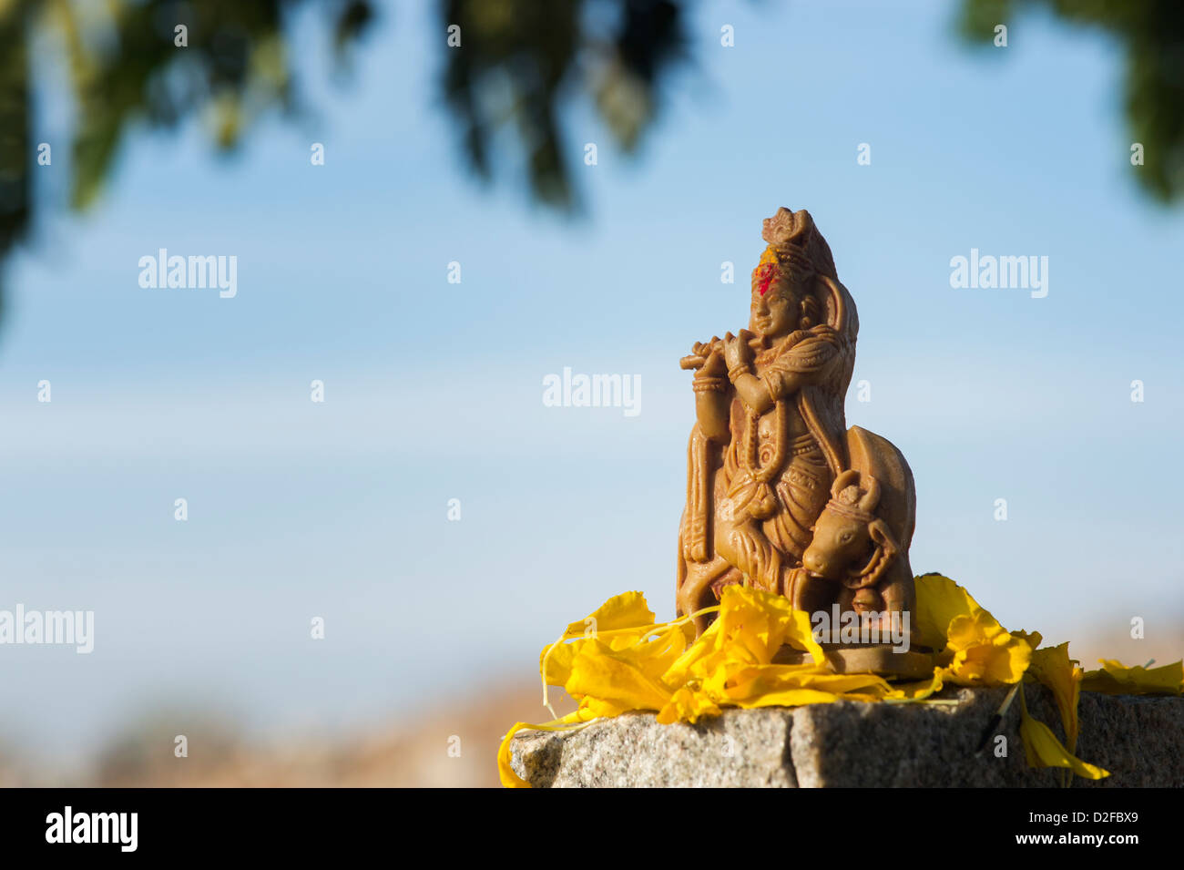 Lord Krishna statue and flower petals against a blue sky. India Stock ...