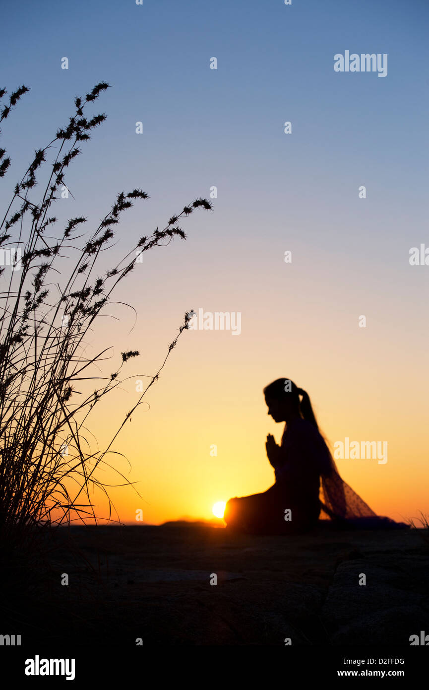 Indian teenage girl praying at sunset in the indian countryside ...