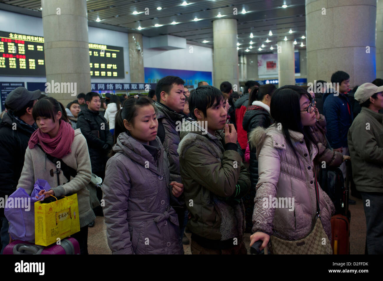 People queue to buy train tickets at a Railway Station in Beijing ...