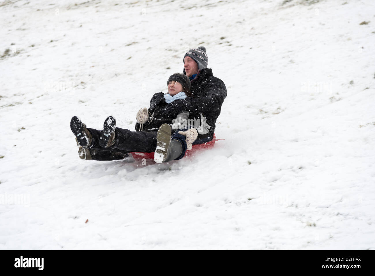 Two people sliding down hillside on sledge after heavy snowfall January ...