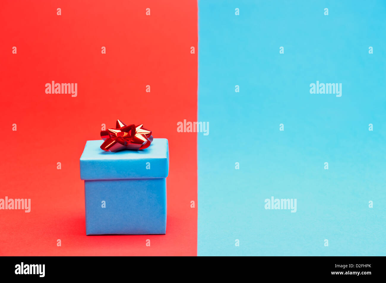 A blue present with a red bow in front of a red blue background Stock ...