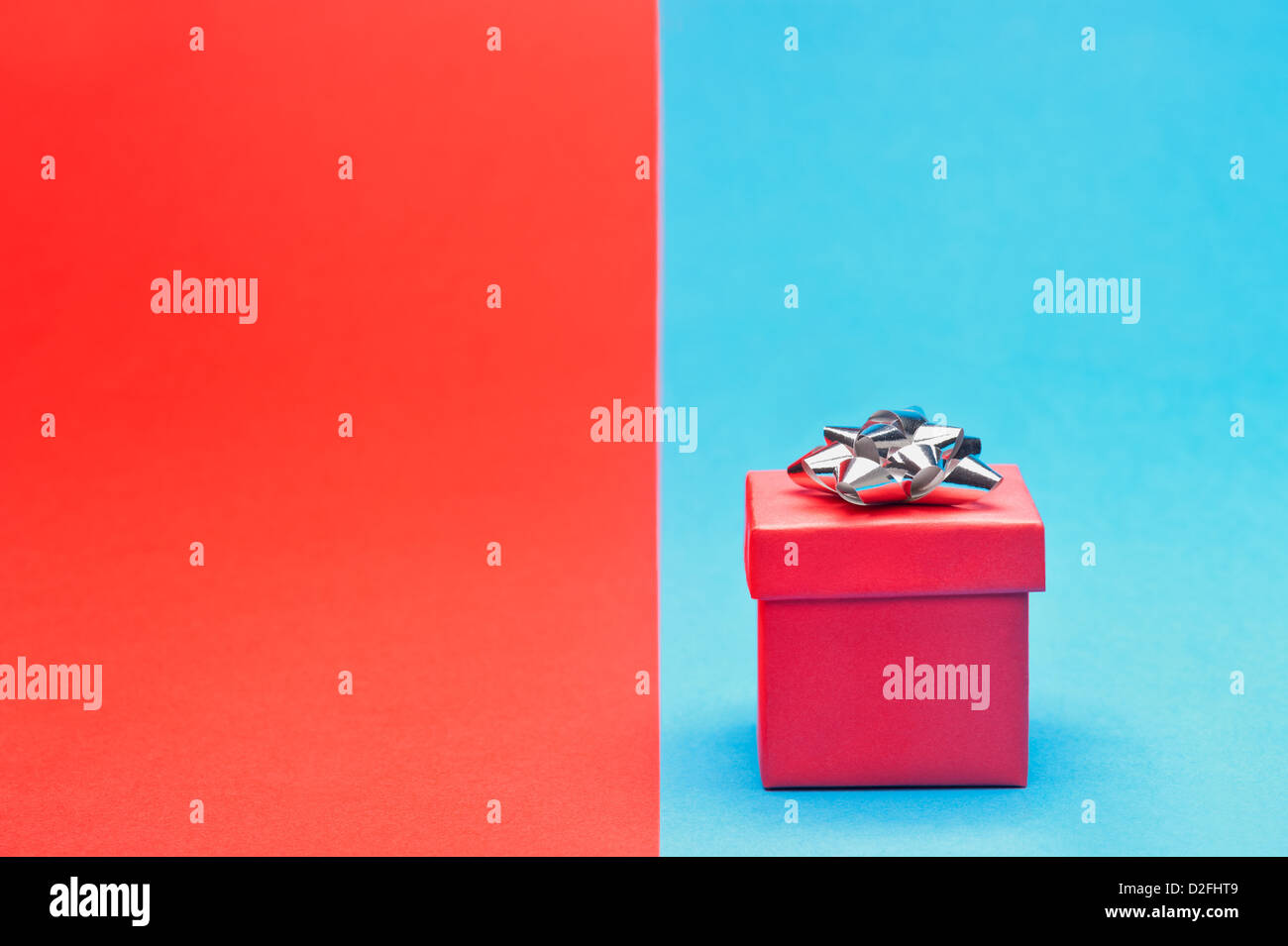 A red present with a silver bow in front of a red blue background Stock ...
