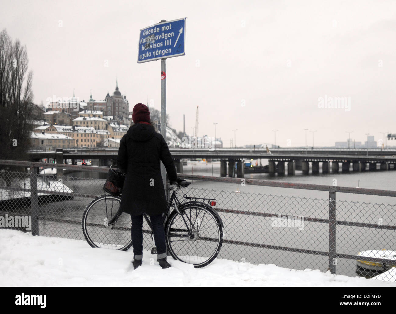 A young woman locks her bike to a railing on the bridge to Soedermalm ...