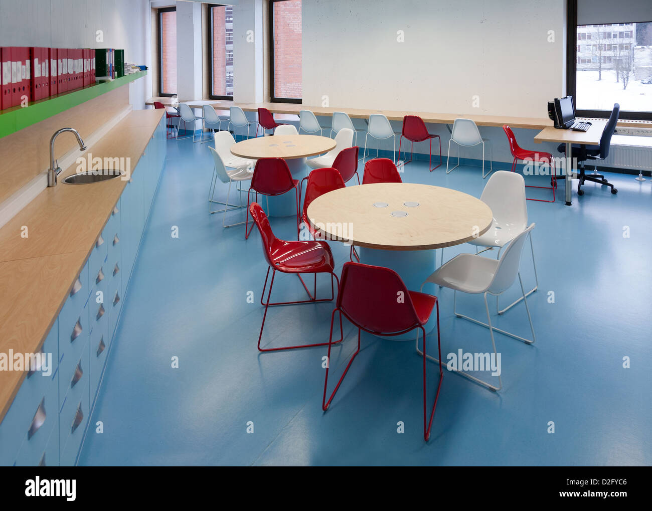 Modern meeting room with colorful chairs, round table, windows and row ...