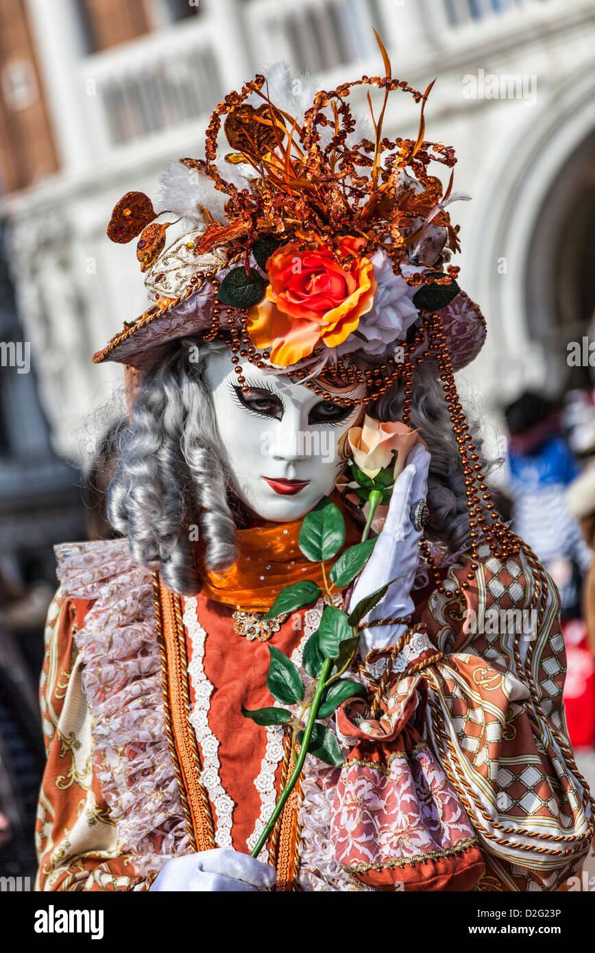 Portrait of a person in a beautiful disguise with an orange rose posing ...