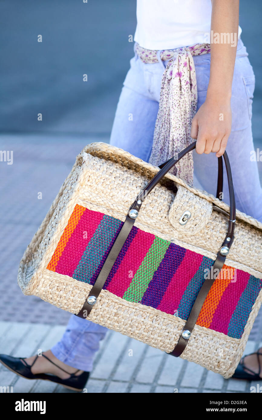 Girl walking carrying straw bag Stock Photo - Alamy