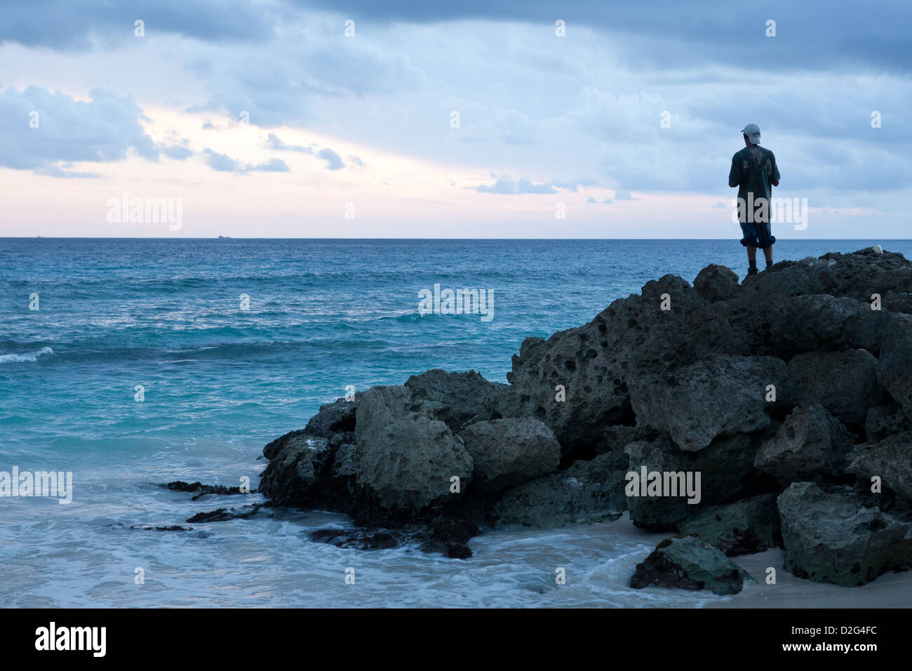 A man looks over the ocean from an outcrop of rocks Stock Photo - Alamy
