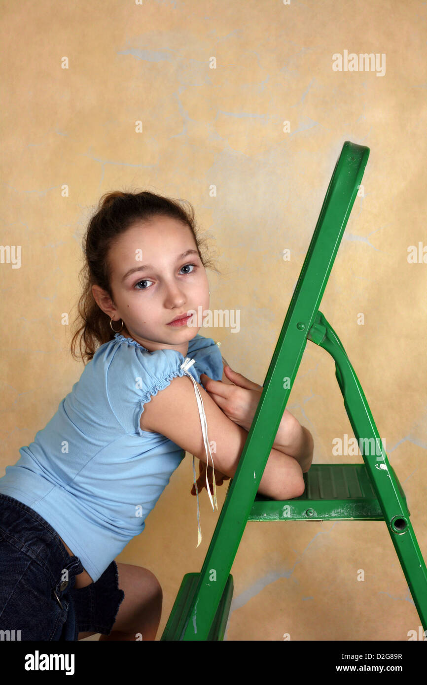 Portrait of the young girl with step-ladder on a yellow background ...