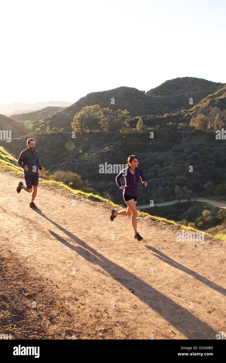 A male and a female runner enjoy a sunset trail run in Griffith Park ...