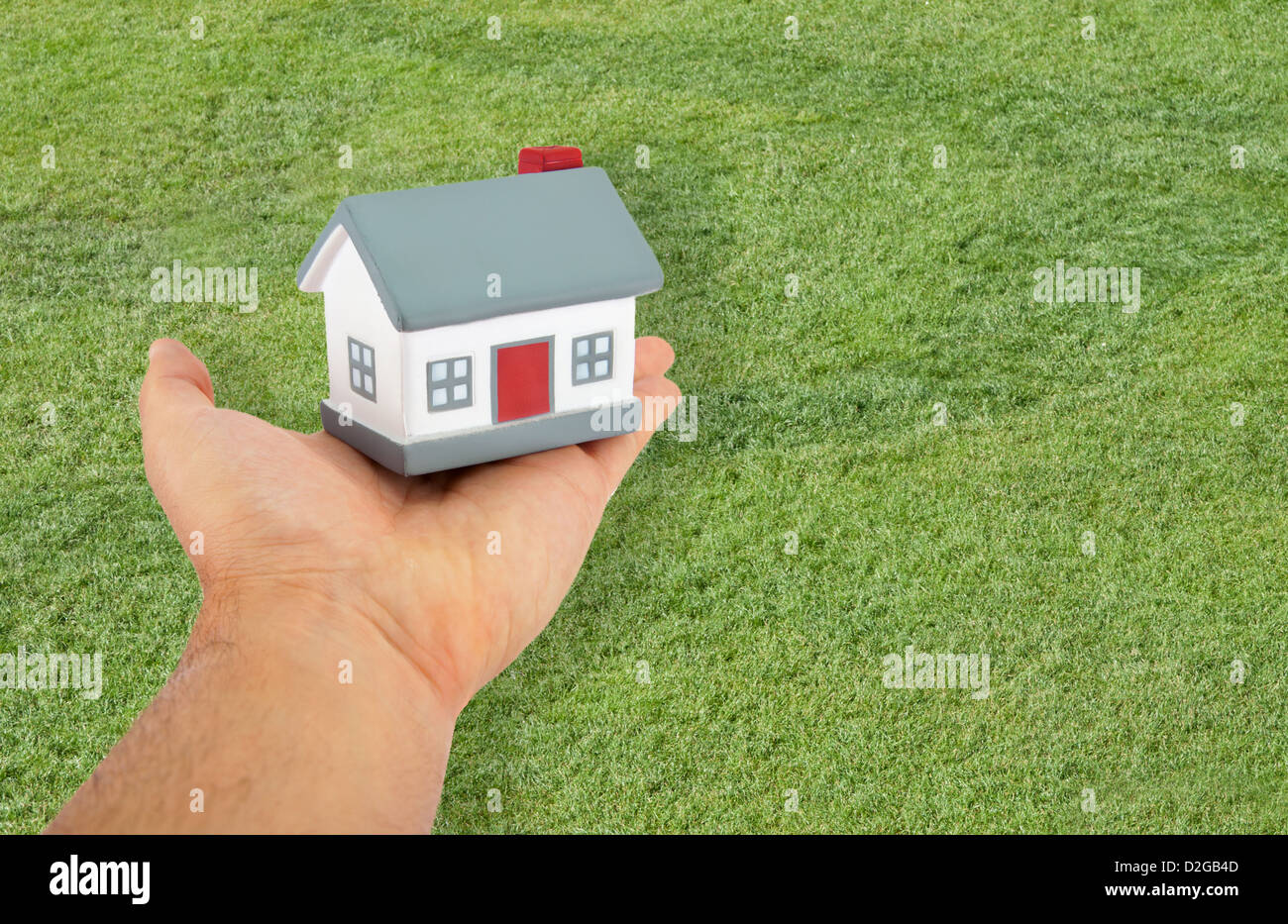 Small house in hand on green background Stock Photo - Alamy