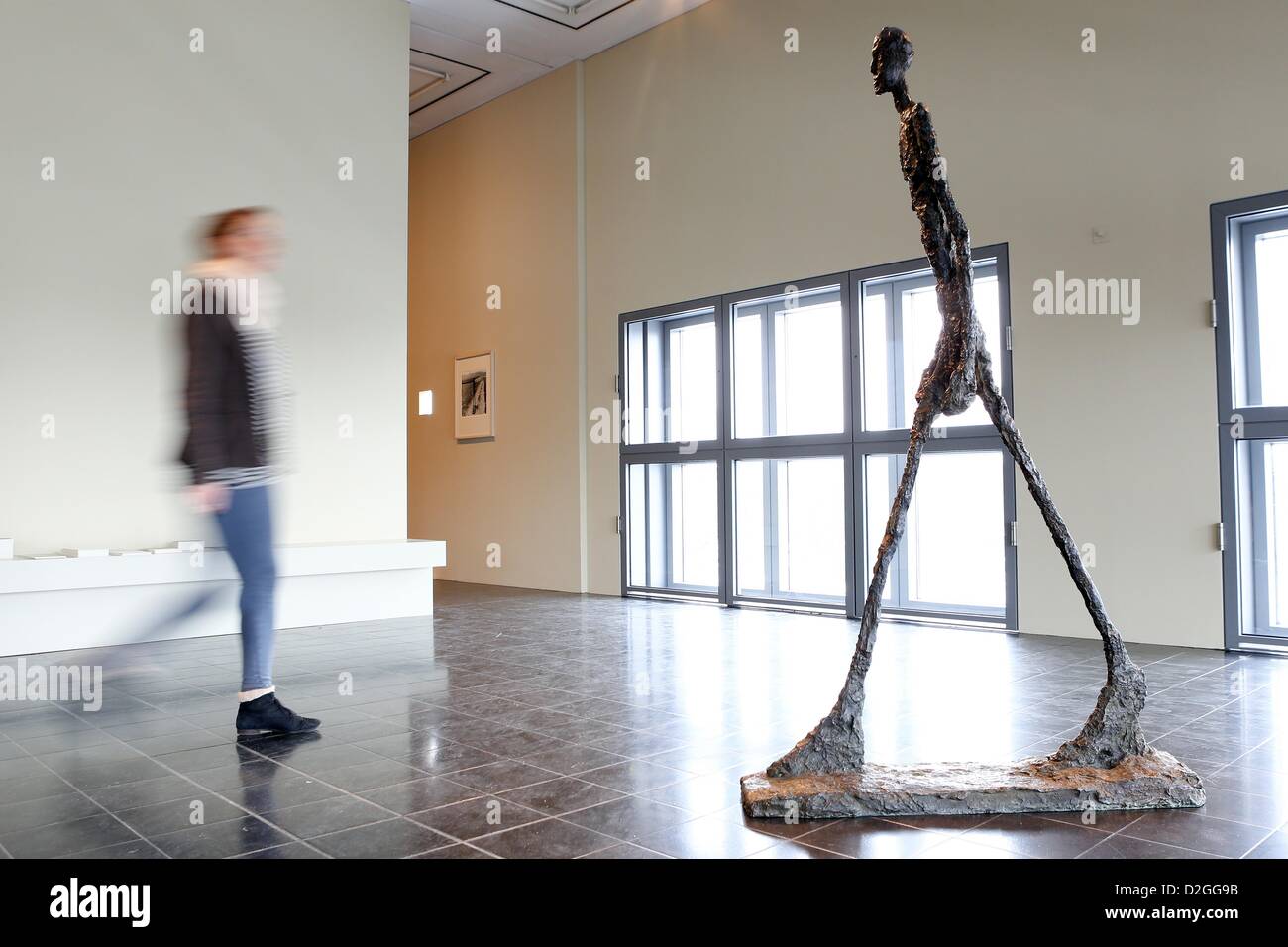 A young woman walks through a room with the sculpture "Walking Man II ...