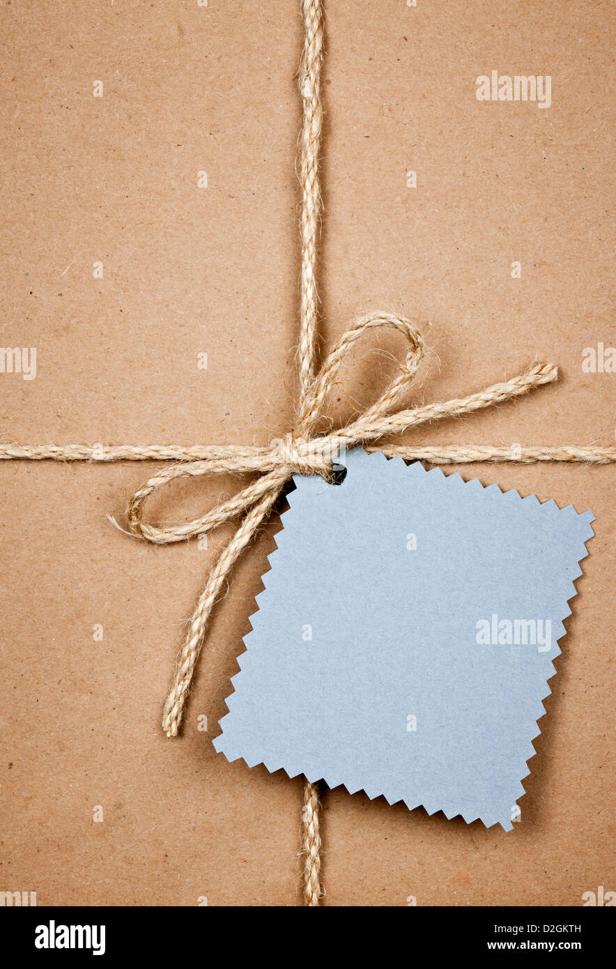 Gift package and blue tag in brown paper wrapper tied with string close ...