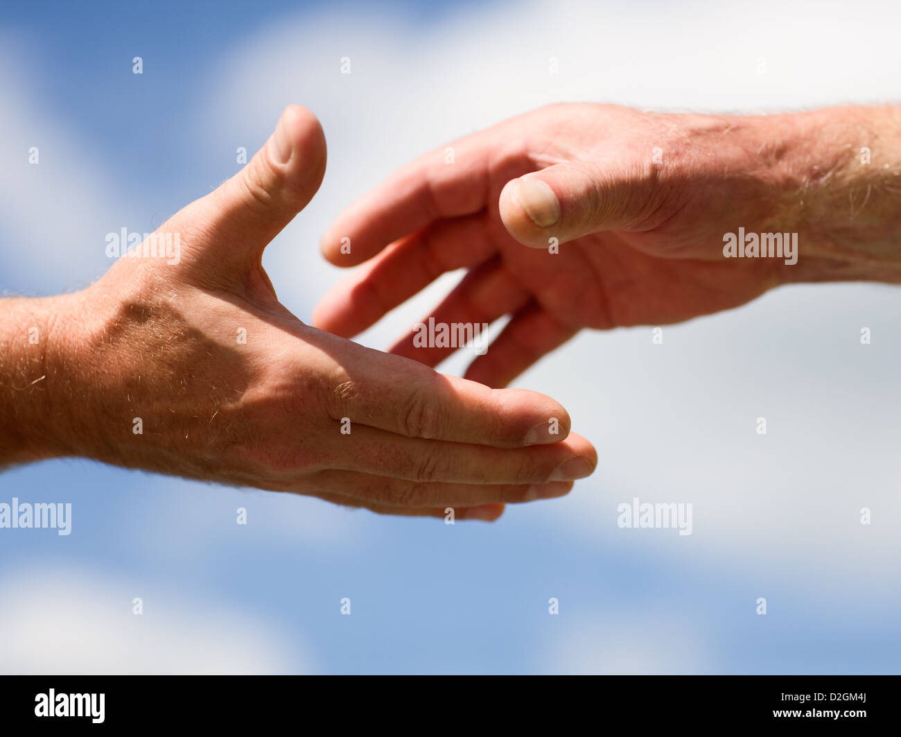 Two hands reaching out to each other against blue sky Stock Photo - Alamy