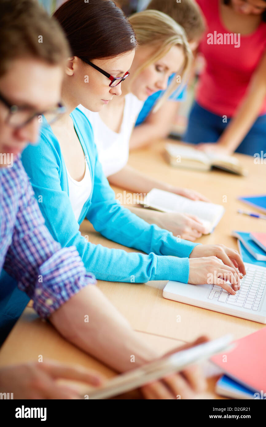 Portrait of pretty girl typing on laptop among her group mates Stock ...