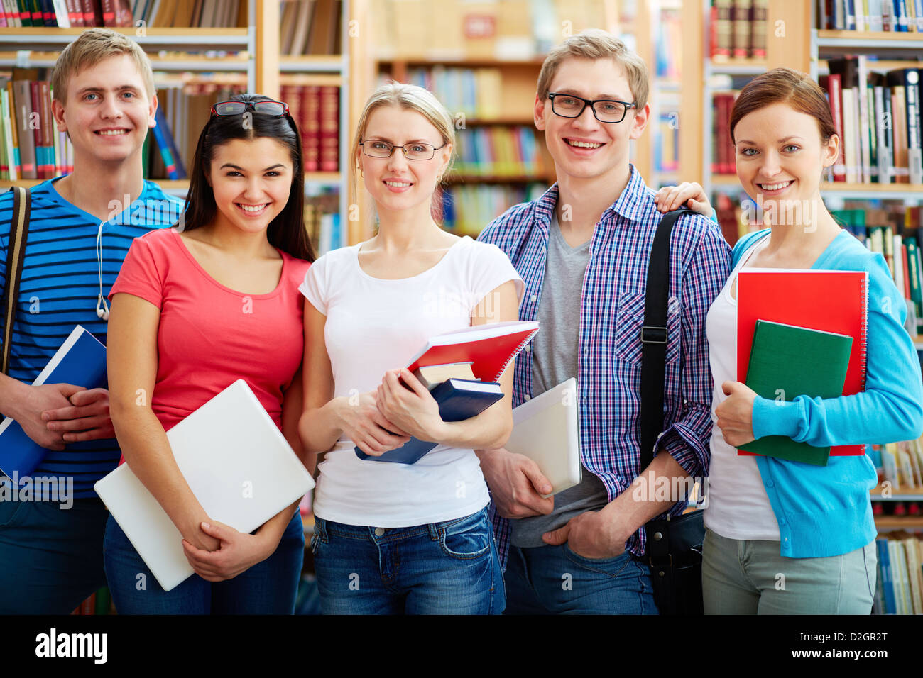 Portrait of friendly students looking at camera in college library ...