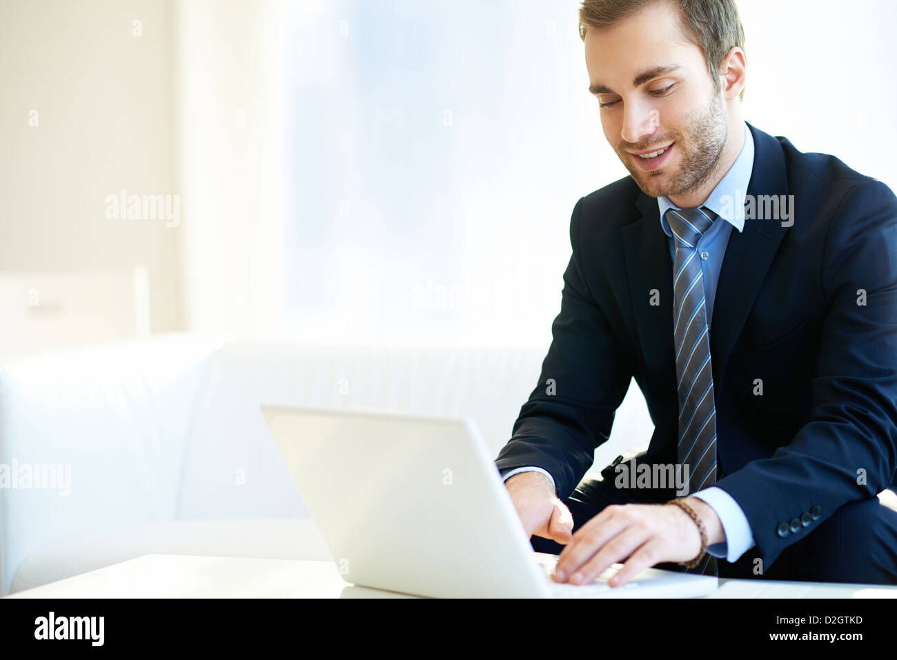 Portrait of attractive businessman in suit typing in office Stock Photo ...