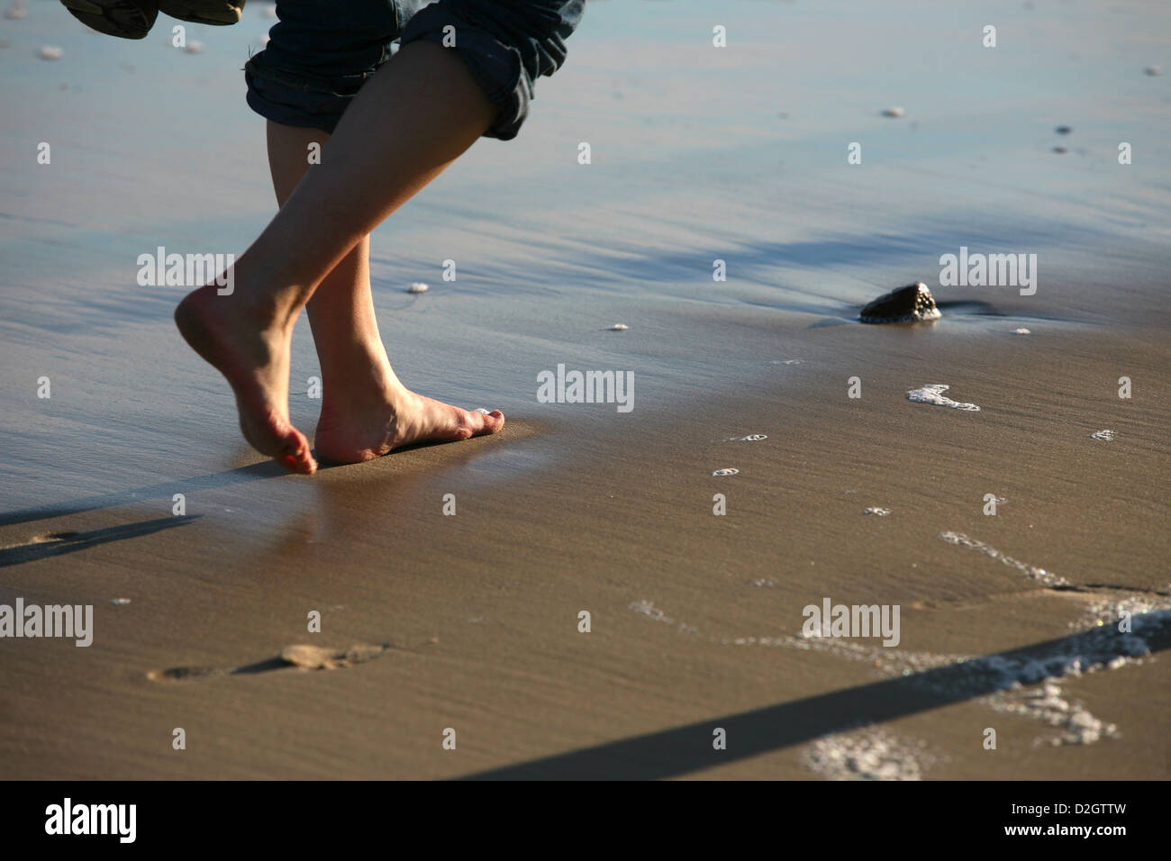 Beach on a sunset. Female legs on damp sand Stock Photo - Alamy