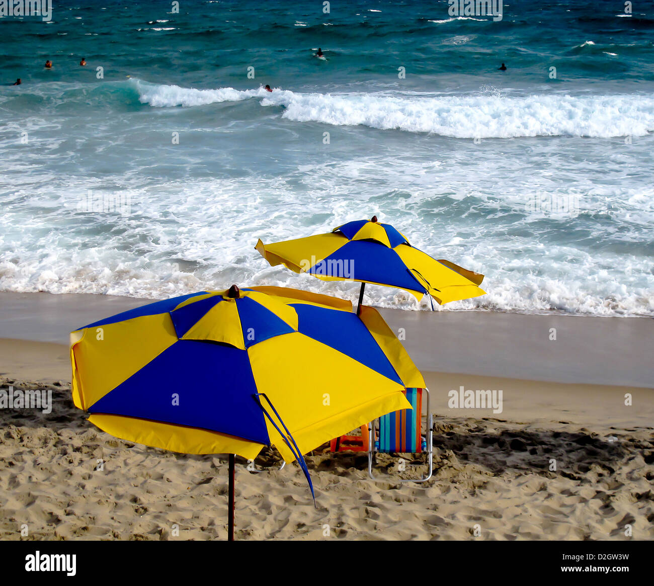 Two yellow and blue parasols and a sun chair on a sandy beach in ...