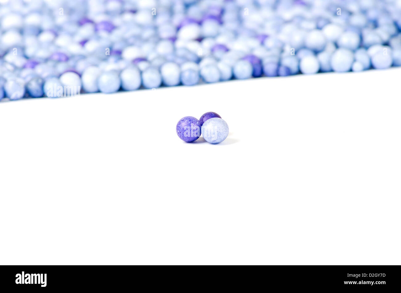 One blue and two violet little pearls isolated on background of other ...