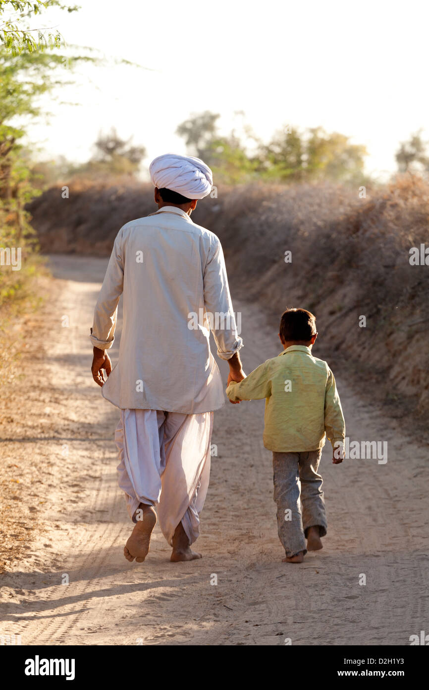 India, Rajasthan, Jodhpur, father and son walking and holding hands ...