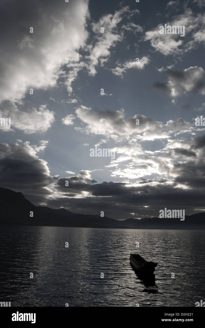 Single wooden boat floating in solitude by the wide open water of Lugu ...