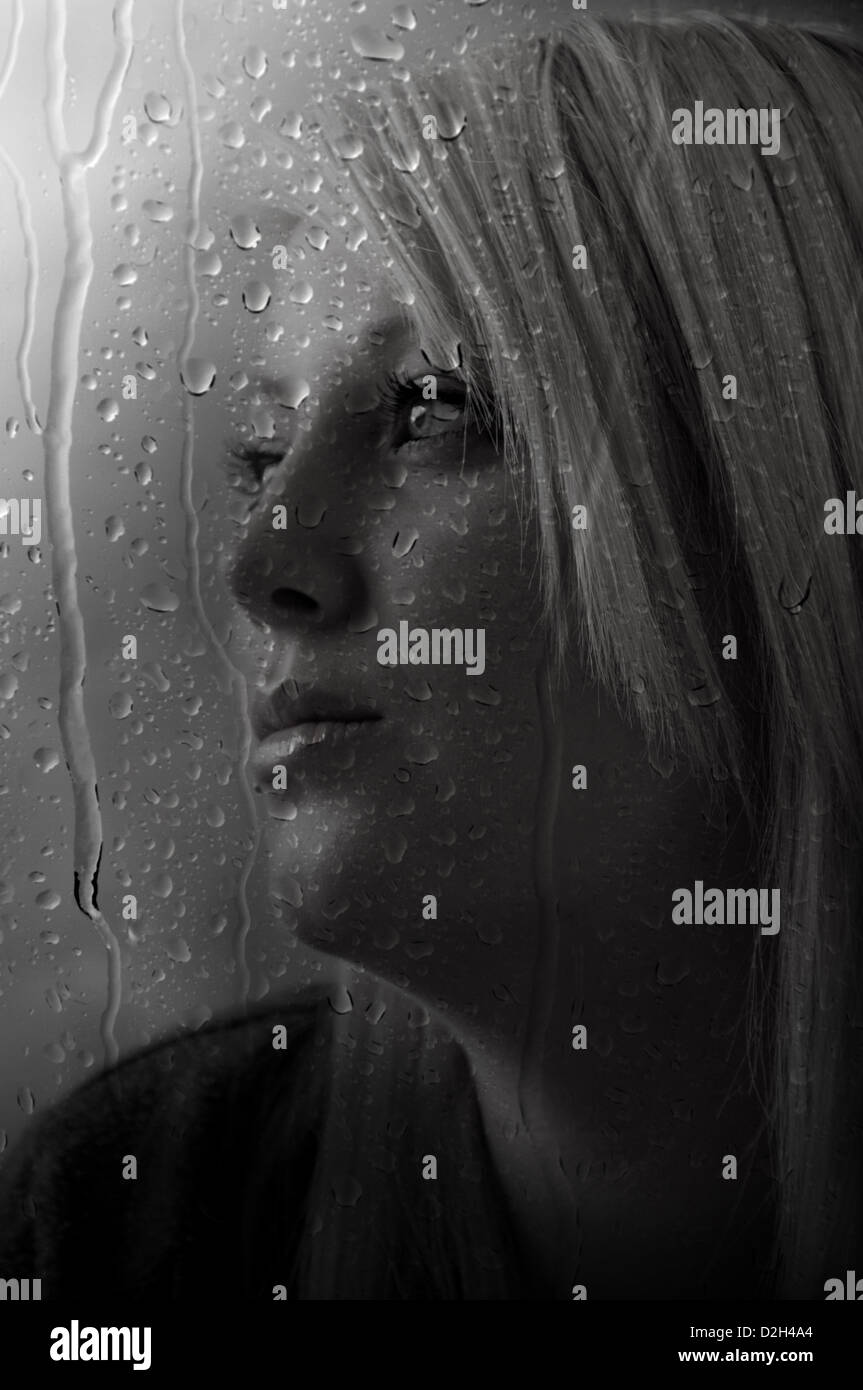 A female model taken through a window with rain drops running down the ...