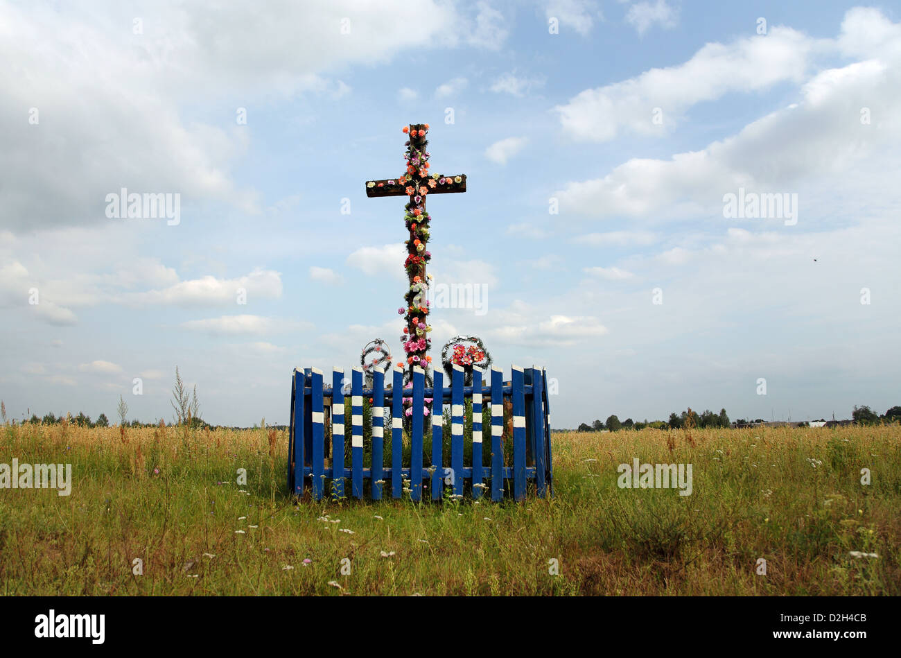 Wadol, Belarus, detached cross adorned with plastic flowers in a meadow ...