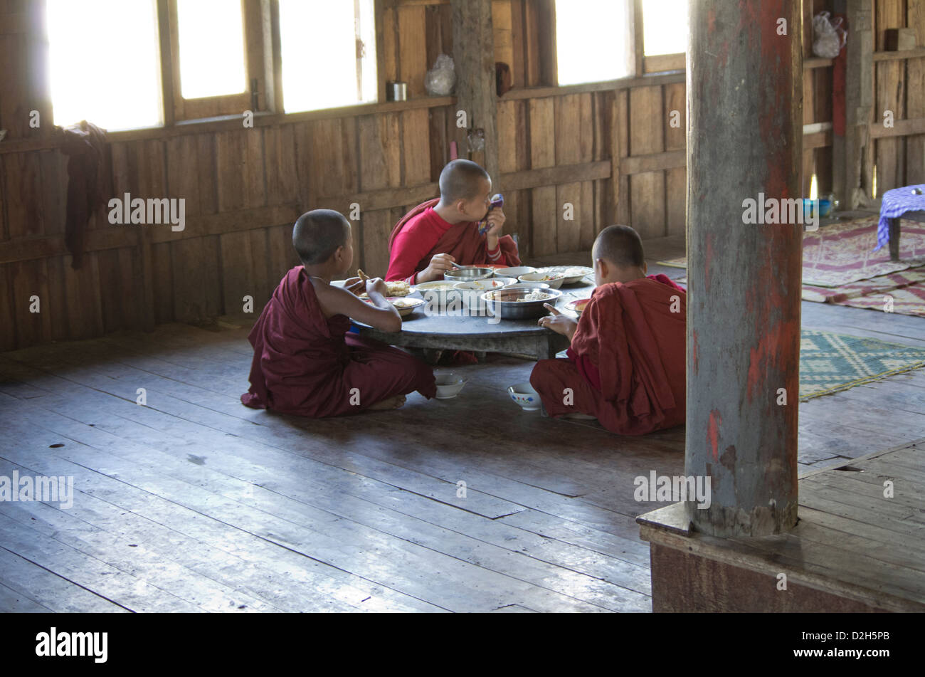 Young Buddhist monks eating lunch in old teak wood monastery Myanmar ...