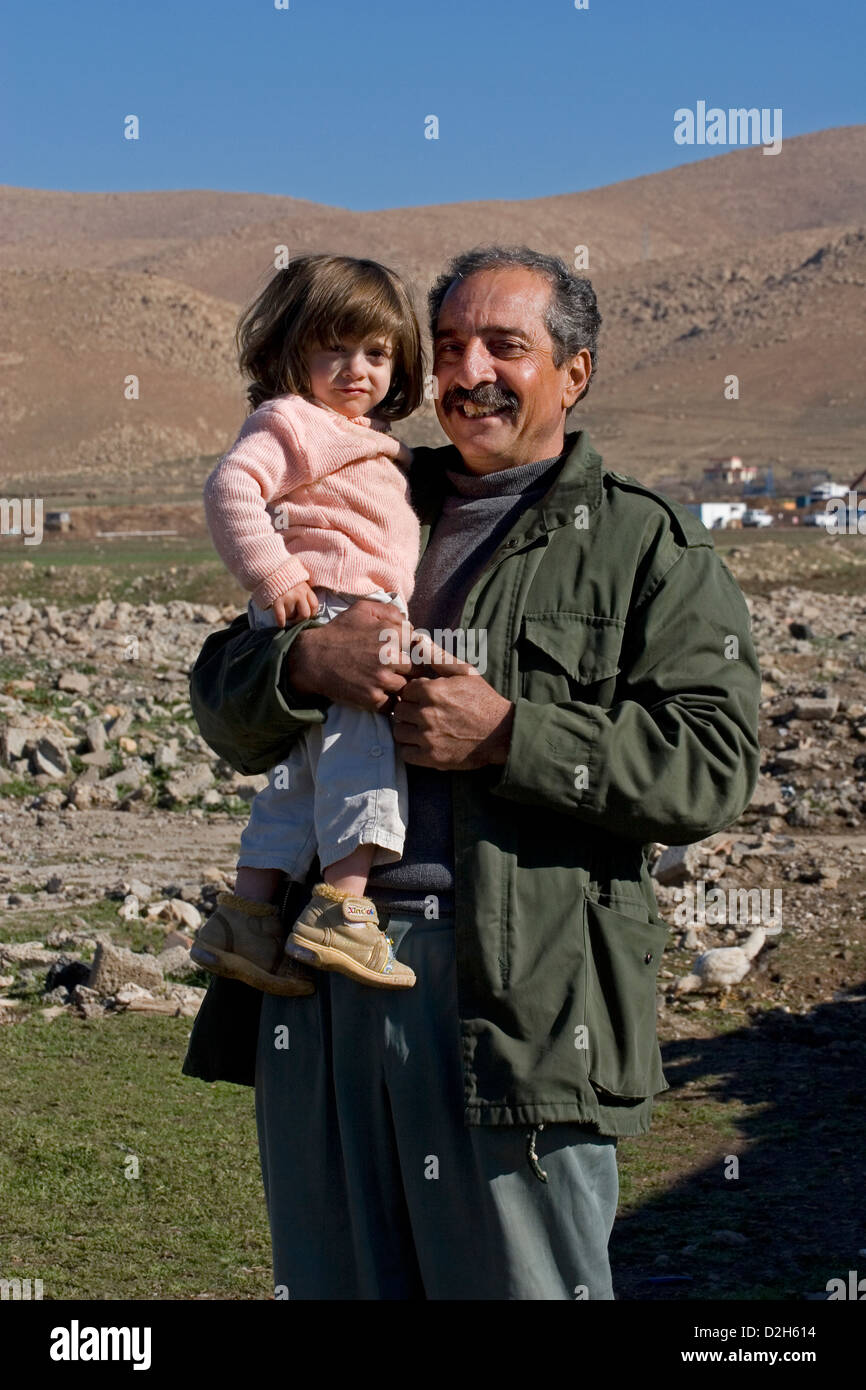 Kurdish refugee grandfather holding 3 year old granddaughter outside in ...