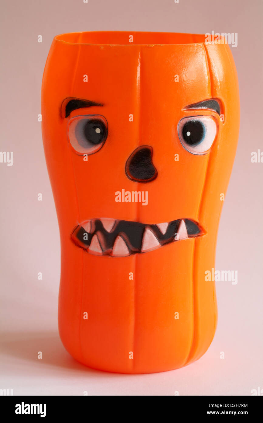 scary halloween face on orange coloured plastic beaker set on white ...