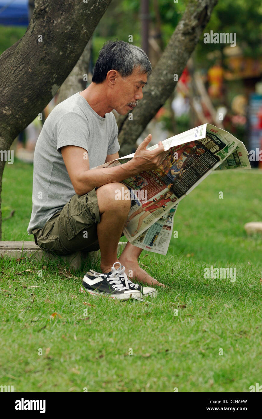 Asian Man reading newspaper outdoors in park Stock Photo - Alamy