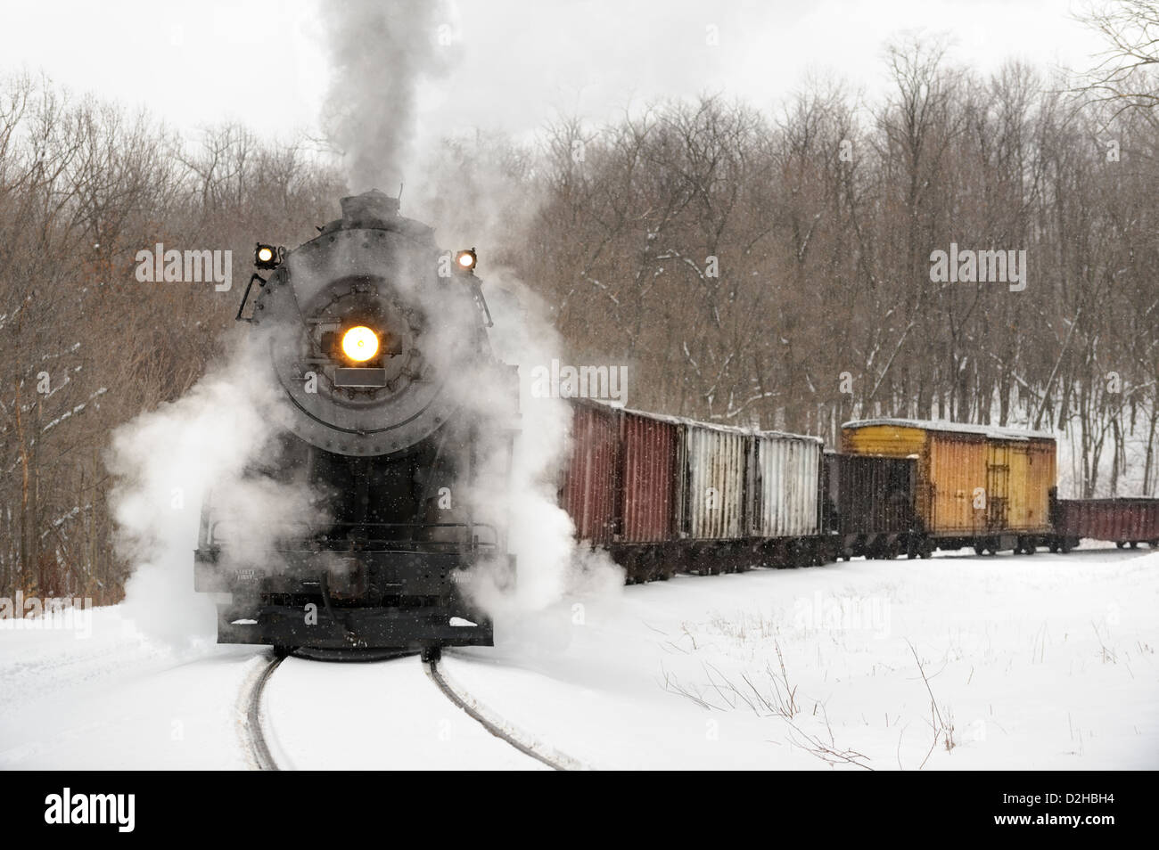 Steam locomotive with freight train rounding mountain curve in falling ...