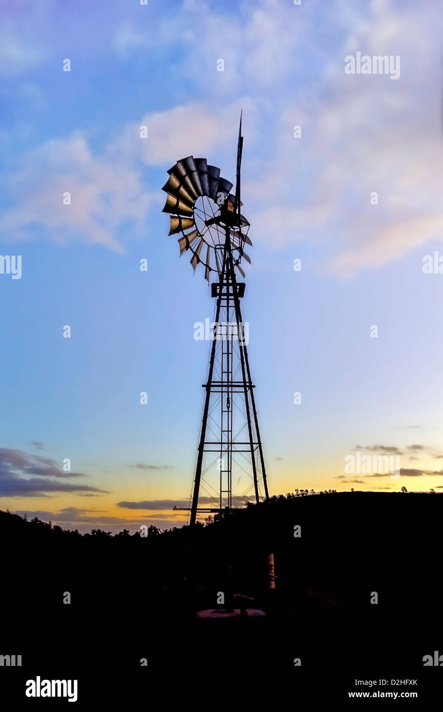 An outback windmill stands motionless and almost silhouetted in the ...