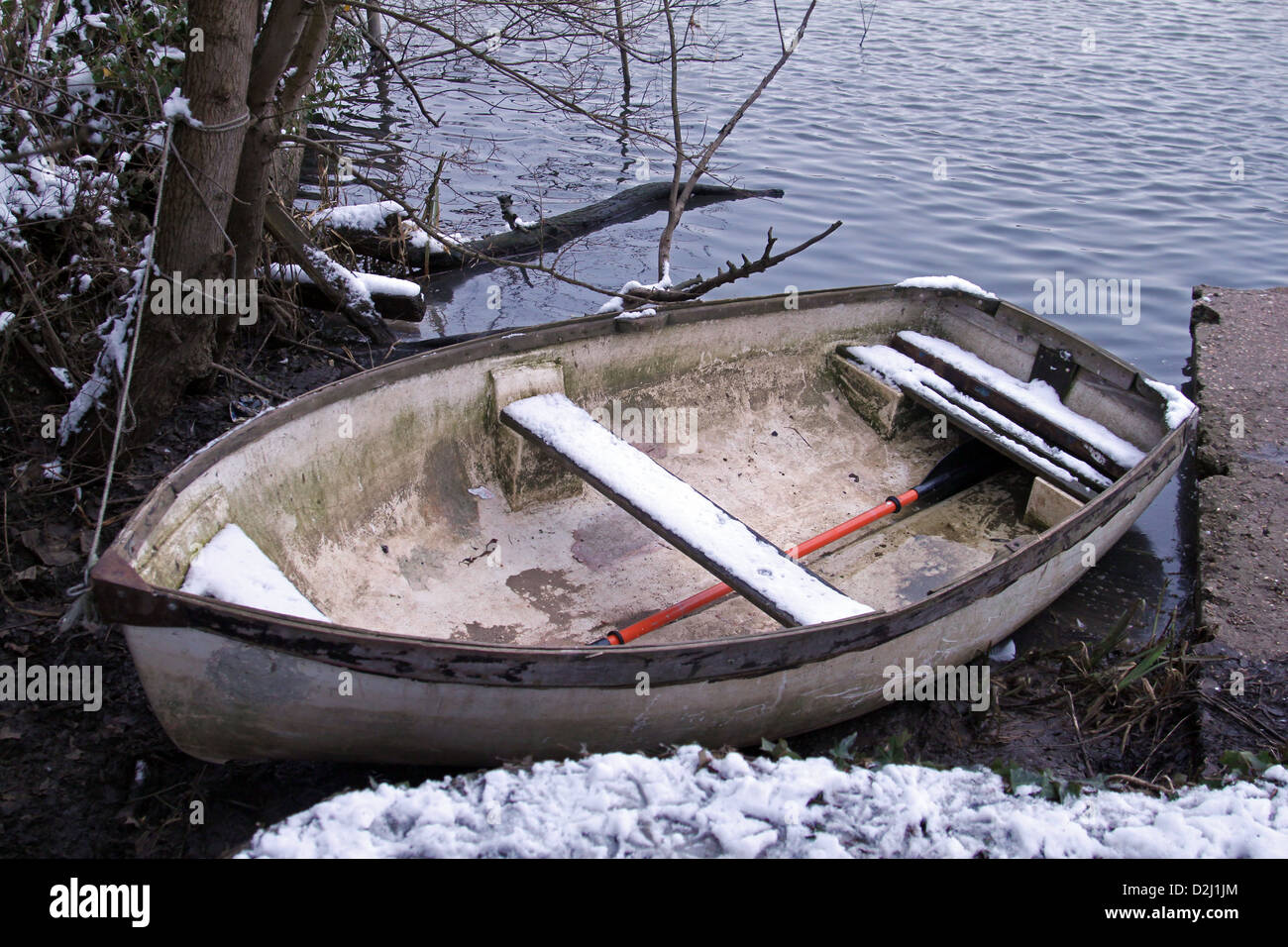 Rowing boat moored by a snowy river bank in England Stock Photo - Alamy