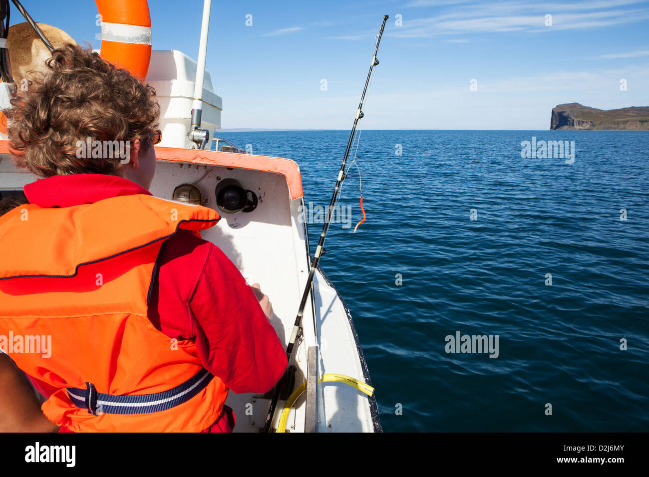 A boy fishing for cod on a boat, in the waters near Hofsós in ...