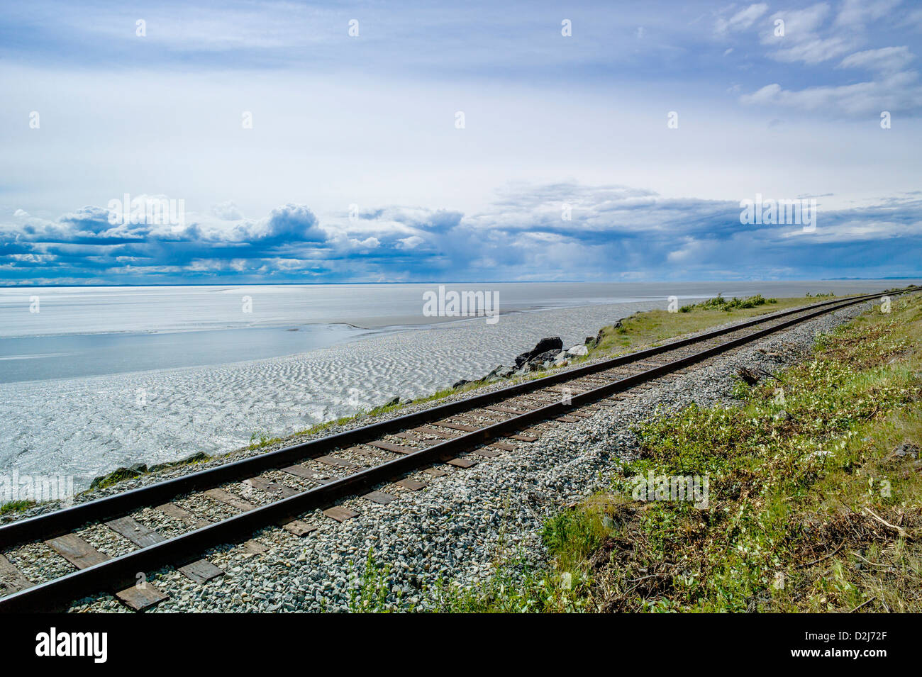 Railroad tracks line the rugged landscape of sea and mountains ...