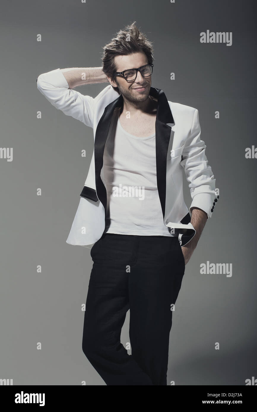 Handsome man casually leaning against the grey wall Stock Photo - Alamy