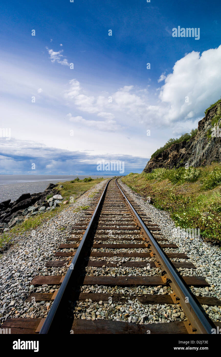 Railroad tracks line the rugged landscape of sea and mountains ...