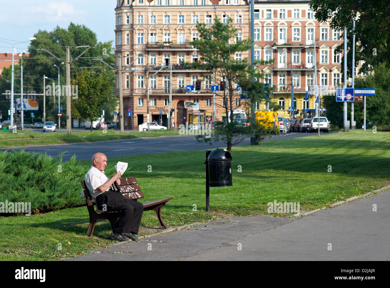 Wroclaw, Poland, an old man sitting on a park bench and reading a ...
