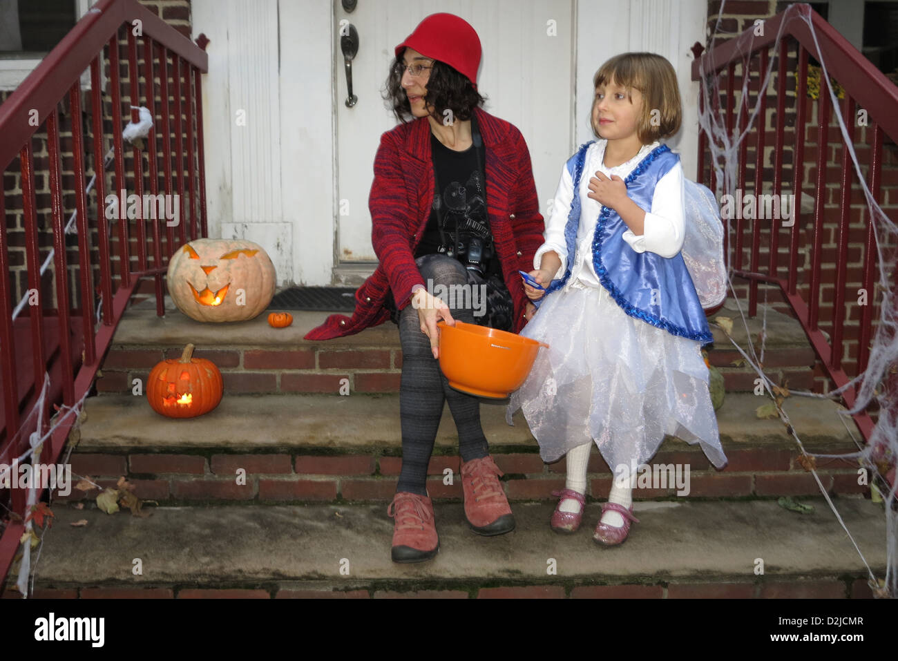 Woman and her daughter giving out Halloween treats from their stoop in ...