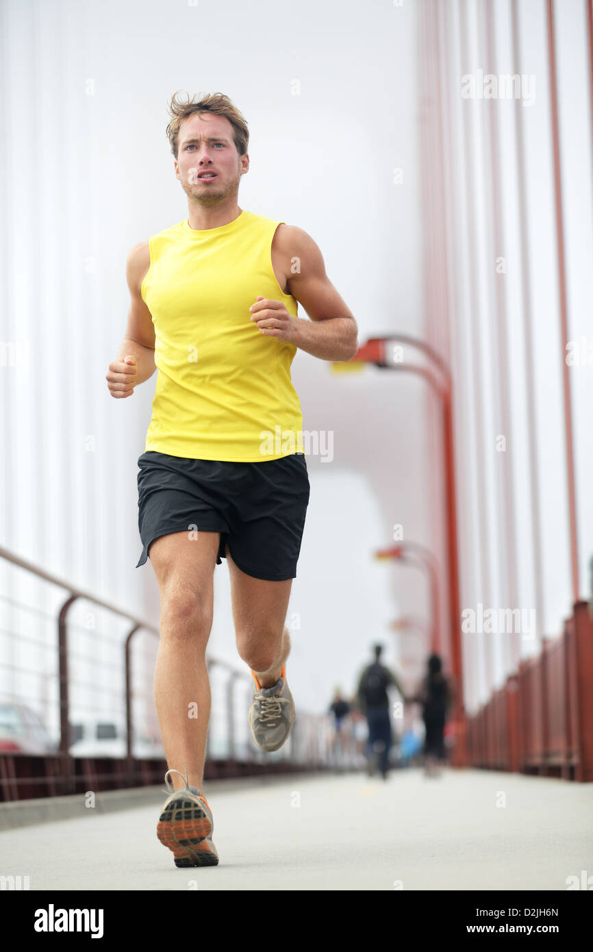 Fit runner running outside. Young male fitness model training in yellow ...