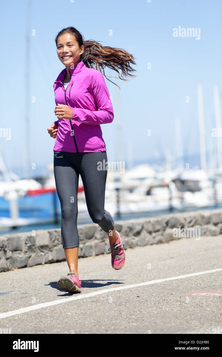 Full length of mixed race happy female athlete training on waterfront ...