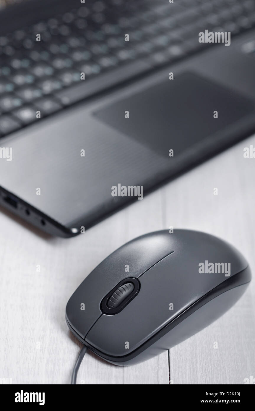 Laptop with computer mouse on the table closeup Stock Photo - Alamy