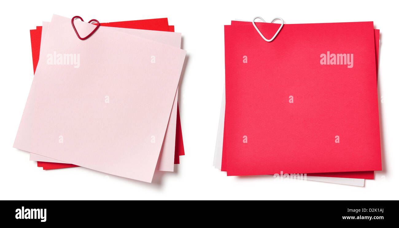 pink and red sticky notes with paper clip in shape of heart on white ...