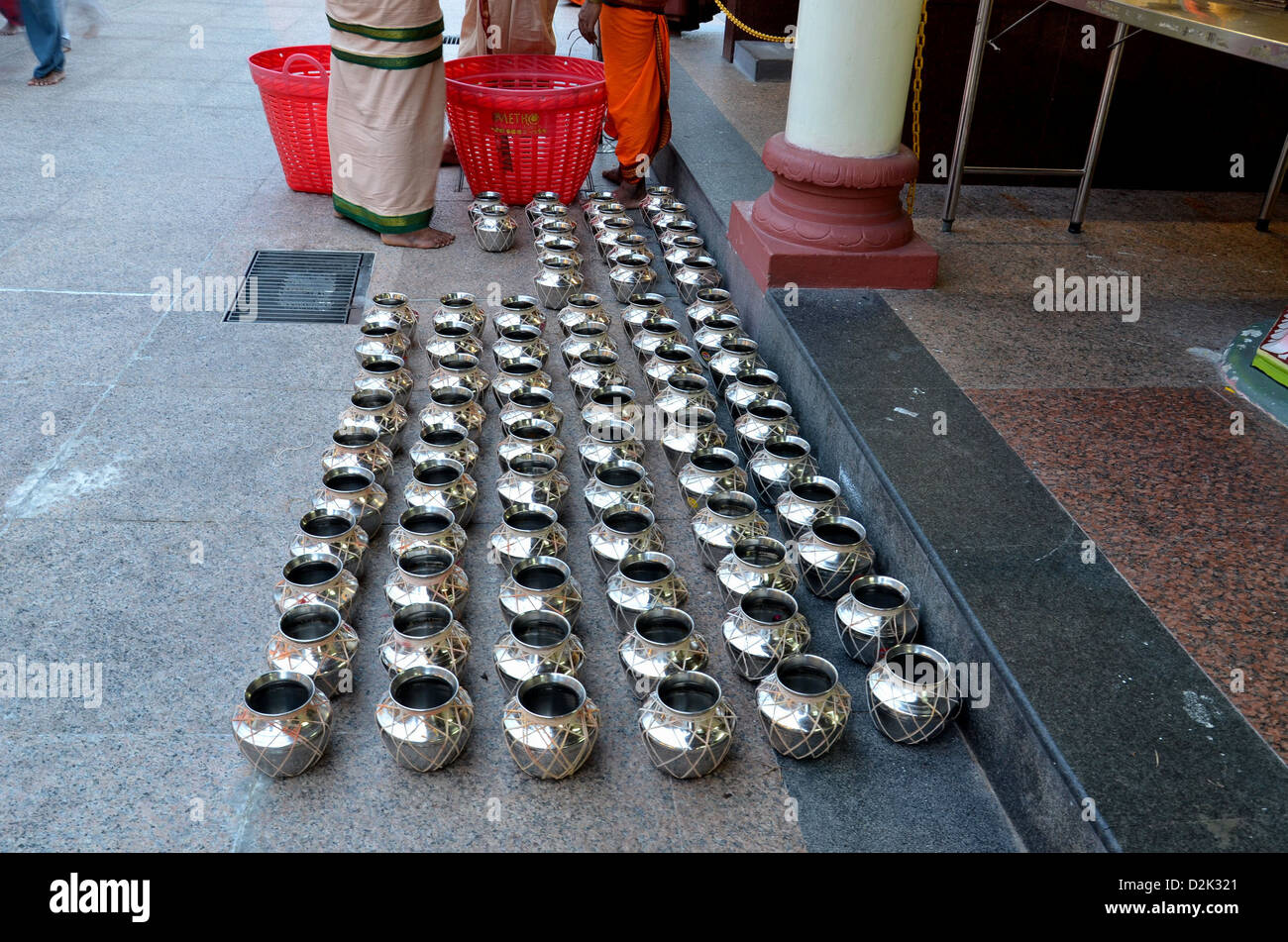 Six lines of silver metal milk offering containers at a Hindu temple ...