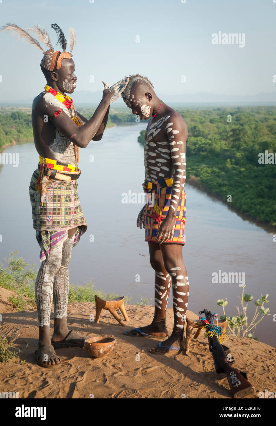 Decorated Kara man painting other man's head-Omo River below Stock ...